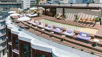 Um lounge no terraço com área de estar ao ar livre, piscina e bar.