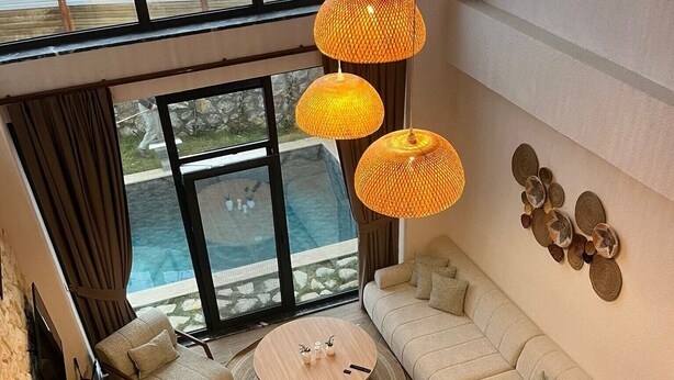Sala de estar moderna com um sofá grande, uma mesa de centro e uma escadaria que leva a uma área externa com piscina.