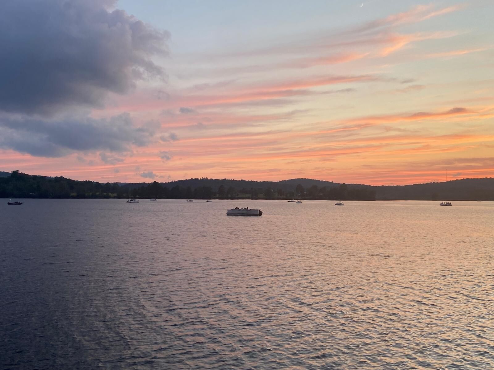 Um lago calmo com barcos ao pôr do sol.