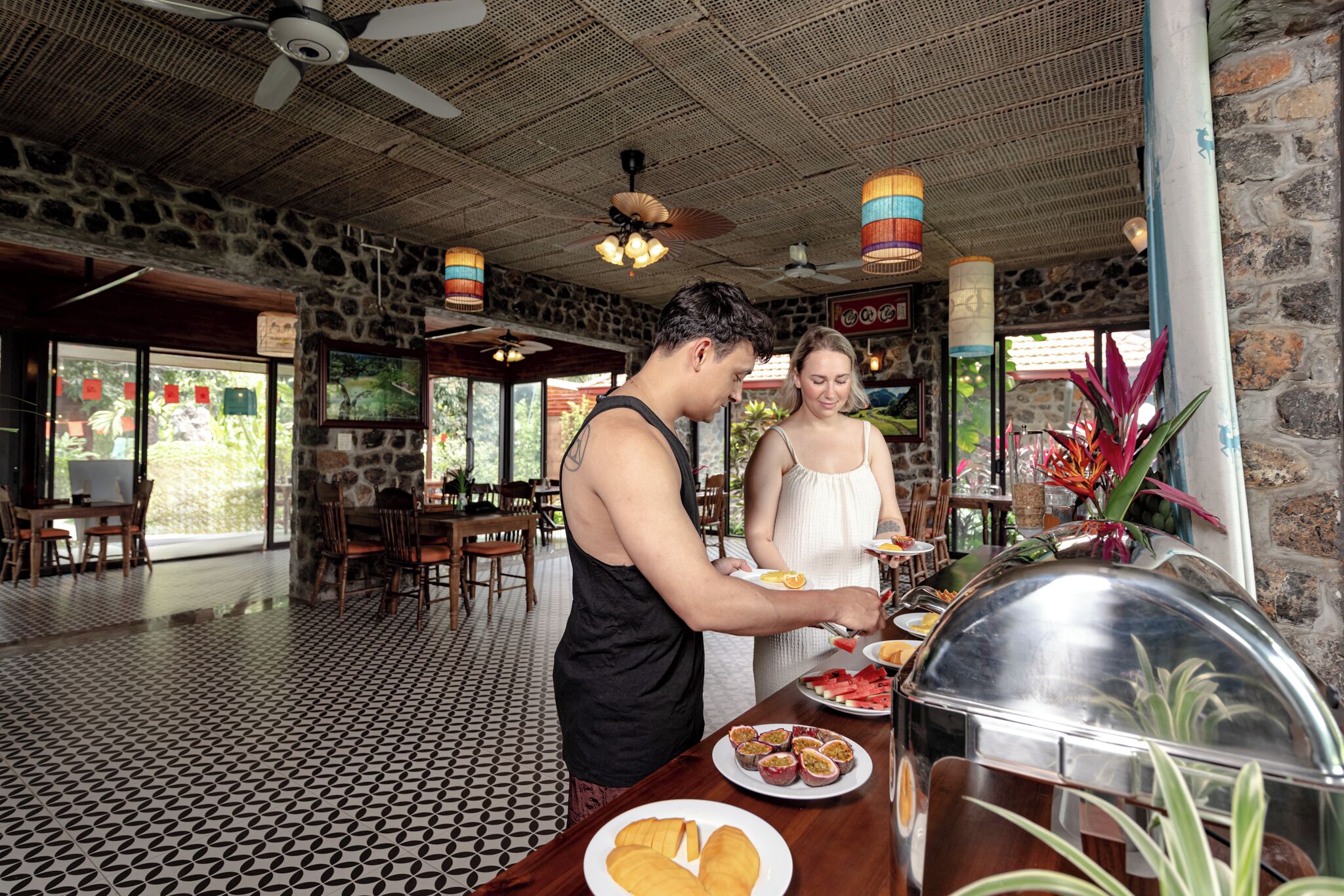 Restaurante com paredes de pedra, pisos ladrilhados e serviço de buffet.
