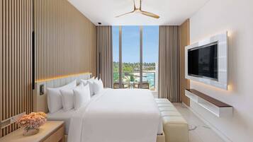 Quarto de hotel moderno com uma cama grande, uma TV na parede e vista para o oceano.