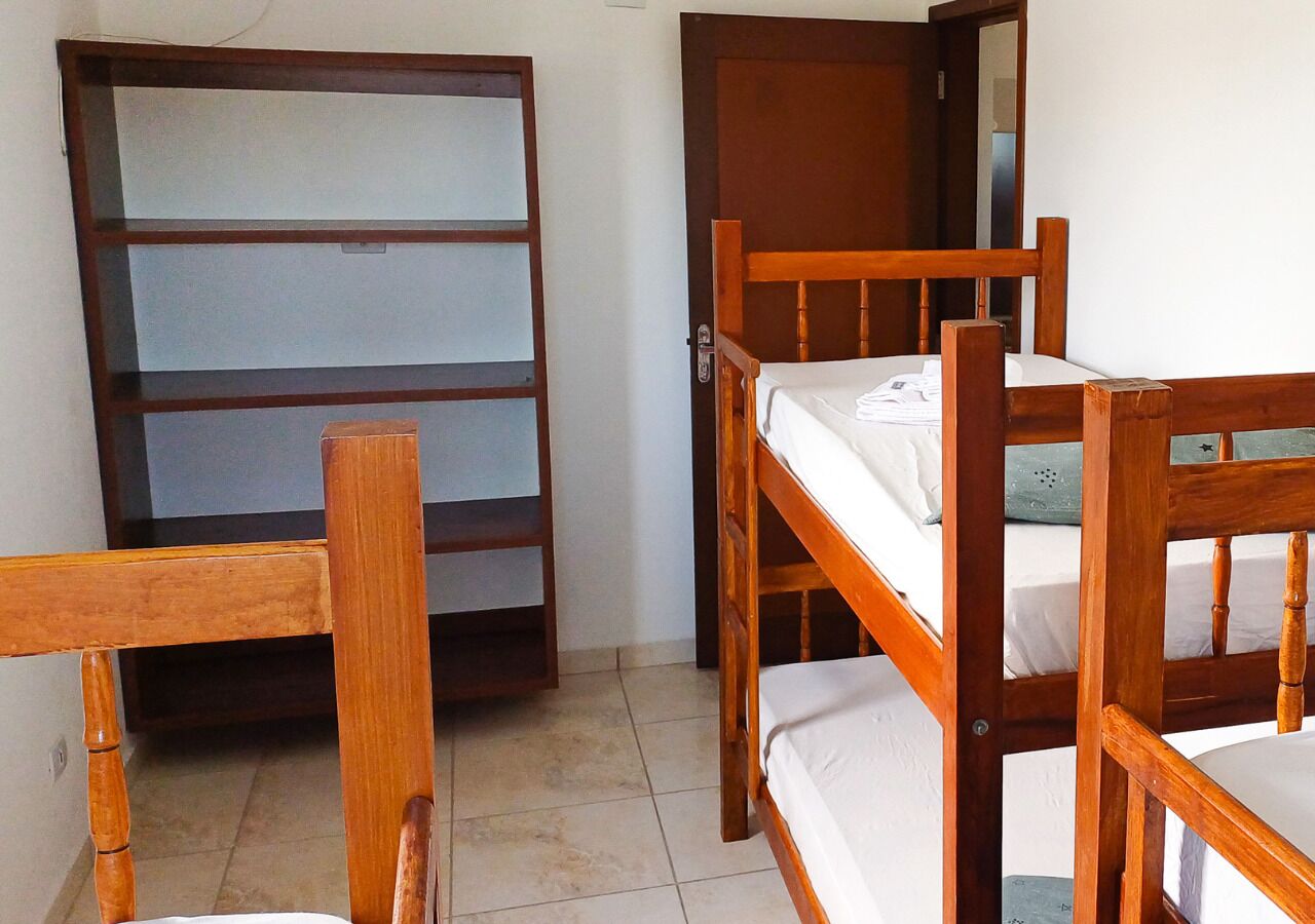 Um quarto com beliches, um guarda-roupa de madeira e uma cadeira.