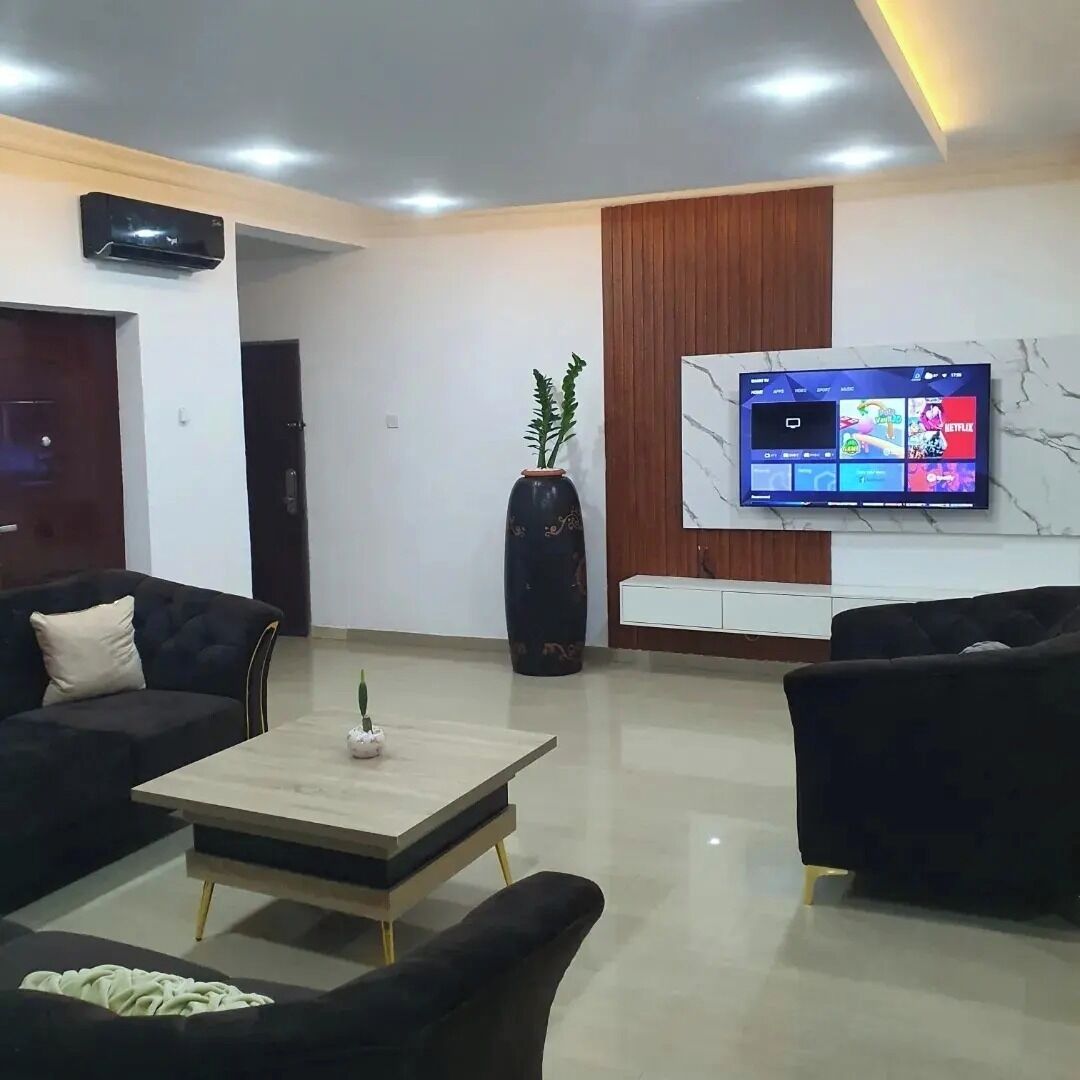 Uma sala de estar moderna com televisão de tela plana na parede, uma mesa de centro e dois sofás.
