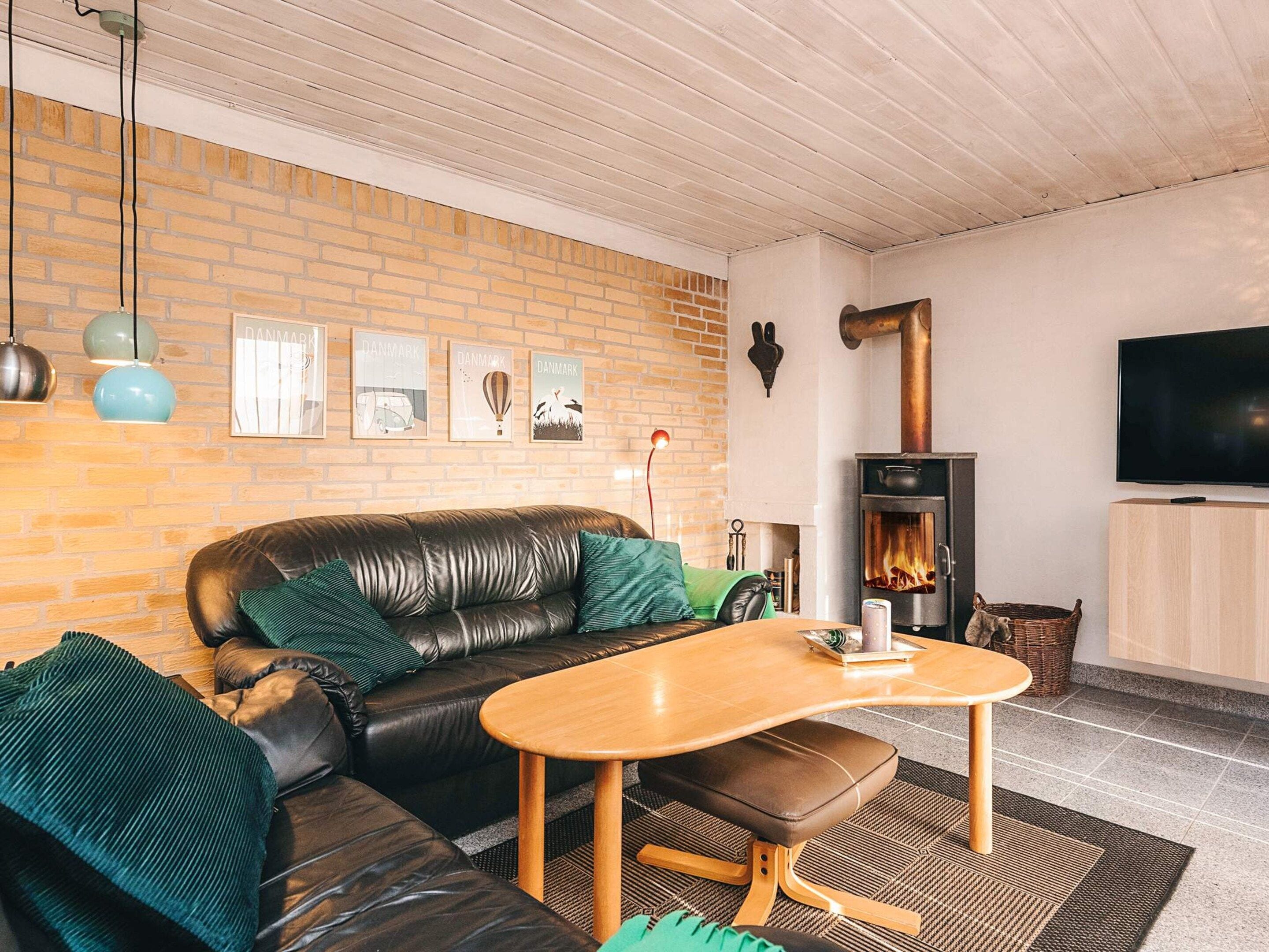 Uma sala de estar aconchegante com um sofá de couro, uma mesa de centro de madeira e uma lareira.