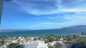 Vista costeira com praia, palmeiras e céu limpo.
