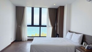Quarto de hotel com uma cama grande, uma mesa de cabeceira e vista para o oceano.