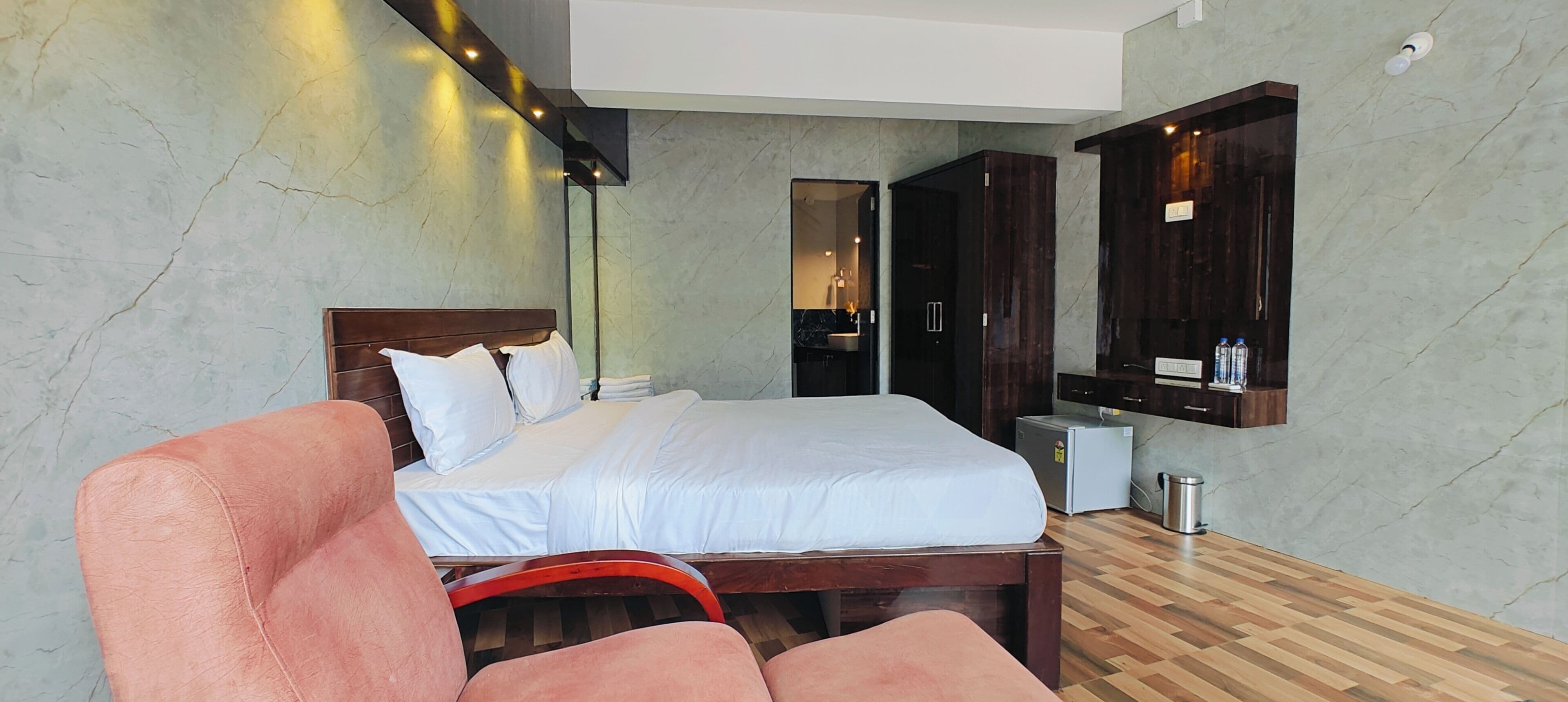Quarto com cama, cadeira, guarda-roupa, espelho e uma pequena mesa.