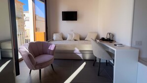 Quarto moderno com cama, escrivaninha, cadeira e televisão.