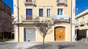 Um edifício com uma placa indicando 'b&b Piazza d'Armi' e 'ASSICURAZIONI'.