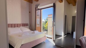 Quarto com cama, porta de vidro deslizante para uma varanda e vista para o exterior.
