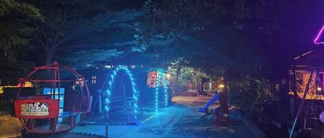 Cena noturna com um teleférico e estruturas iluminadas, possivelmente parte de um parque ou atração turística.