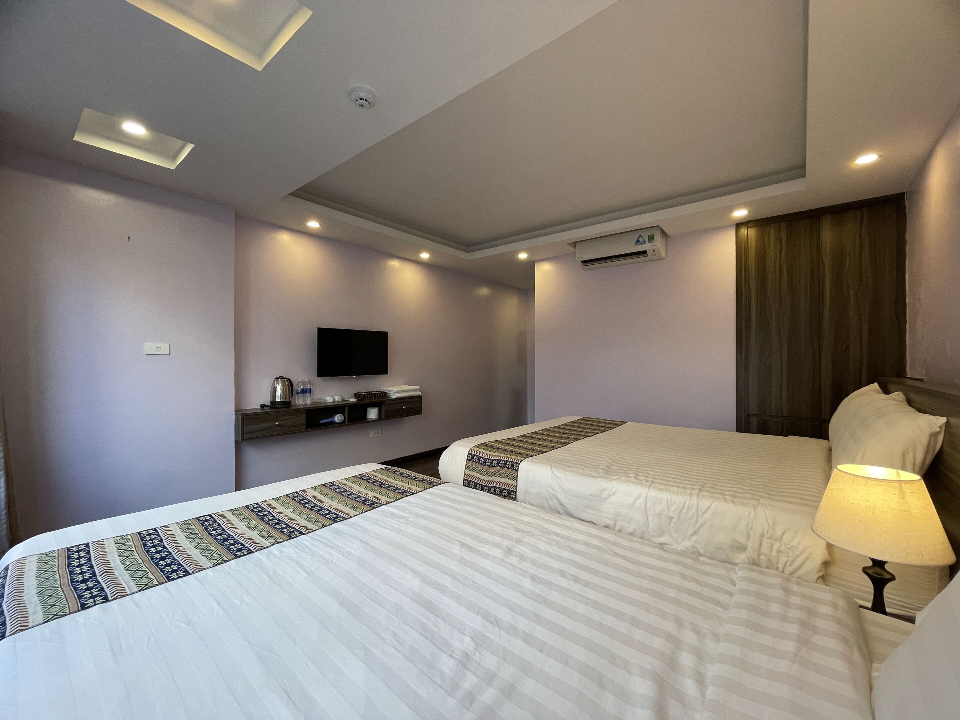 Quarto de hotel com duas camas, televisão de tela plana, minibar e ar condicionado.