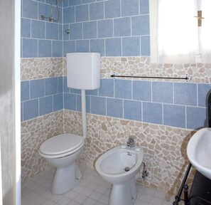 Casa de banho com duas sanitas, um bidé e uma pia.