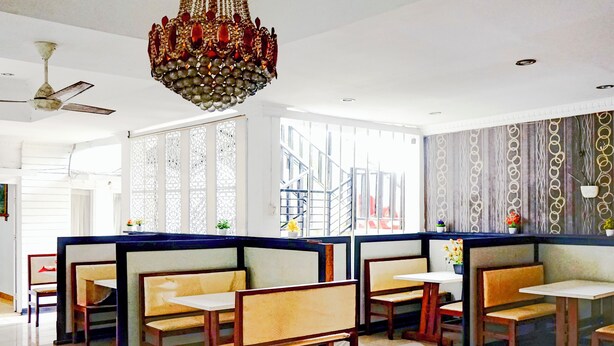 Um restaurante com cabines, um candelabro e uma escadaria ao fundo.