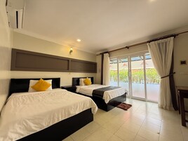 Quarto de hotel com duas camas, uma janela grande com cortinas e vista para o exterior.