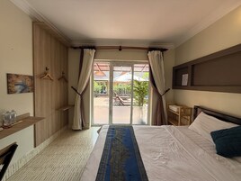 Quarto de hotel com uma cama, uma escrivaninha, uma cadeira e vista para o exterior.