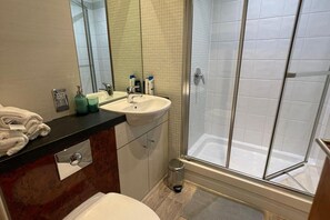 Casa de banho moderna com lavatório, espelho e cabine de duche em vidro.
