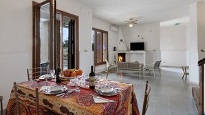 Uma sala de jantar com uma mesa posta para dois, lareira e televisão ao fundo.