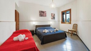 Quarto de hotel com duas camas, uma cadeira de madeira e uma janela.