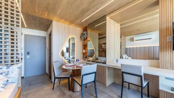 Quarto moderno e bem iluminado, com teto de madeira, área de jantar com duas cadeiras e uma mesa, um espelho grande e um ar condicionado embutido.