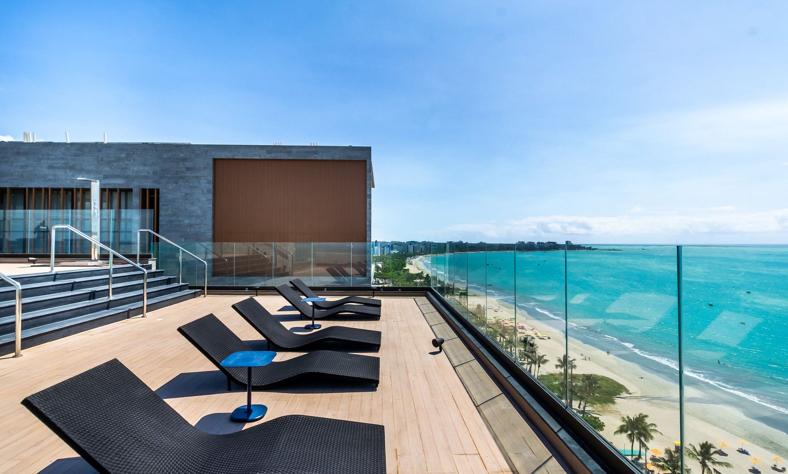 Terraço no telhado com espreguiçadeiras e vista para a praia.