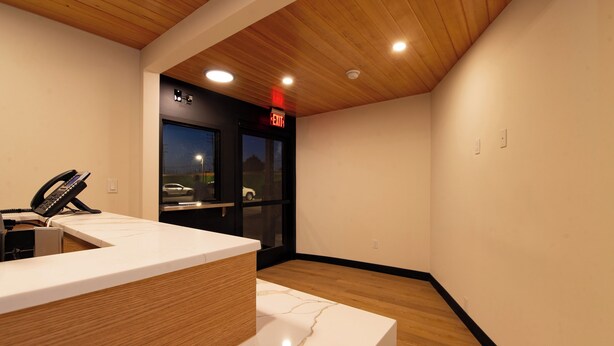 Uma área de recepção de hotel com teto de madeira, balcão de atendimento e vista para o exterior.