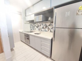 Uma cozinha moderna com frigorífico de aço inoxidável, micro-ondas e forno embutido.