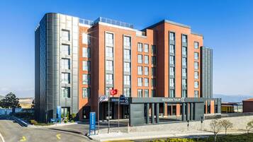 Um hotel com vários andares e design moderno, com entrada e sinalização chamativas para 'Golden Tulip'.