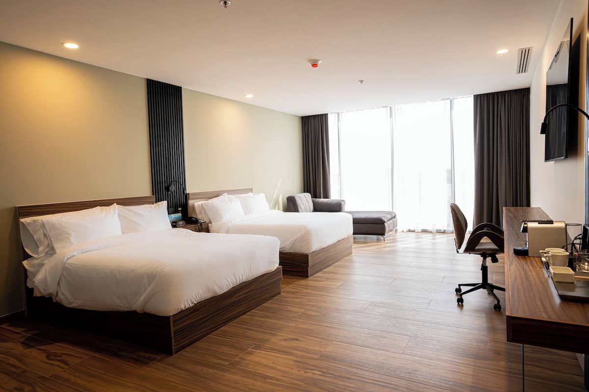 Quarto de hotel moderno com duas camas, uma escrivaninha e uma cadeira.