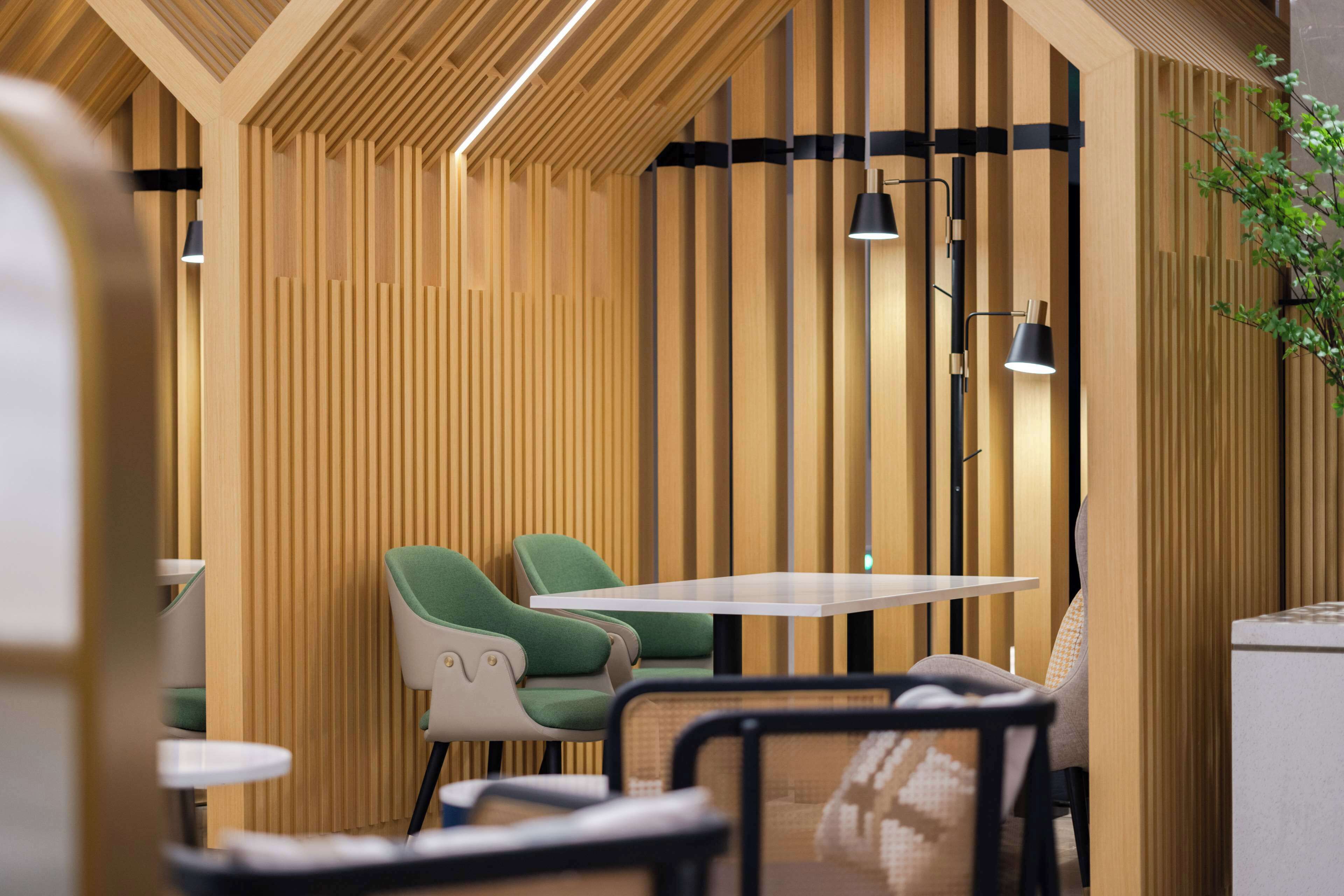 Um interior moderno com painéis de parede de madeira, cadeiras verdes e brancas e uma mesa branca.