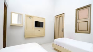 Quarto com duas camas, televisão na parede, guarda-roupa e espelho.