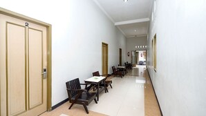 Um corredor com duas portas, numeradas 2 e 3, que dá para uma sala de jantar com mesas e cadeiras.