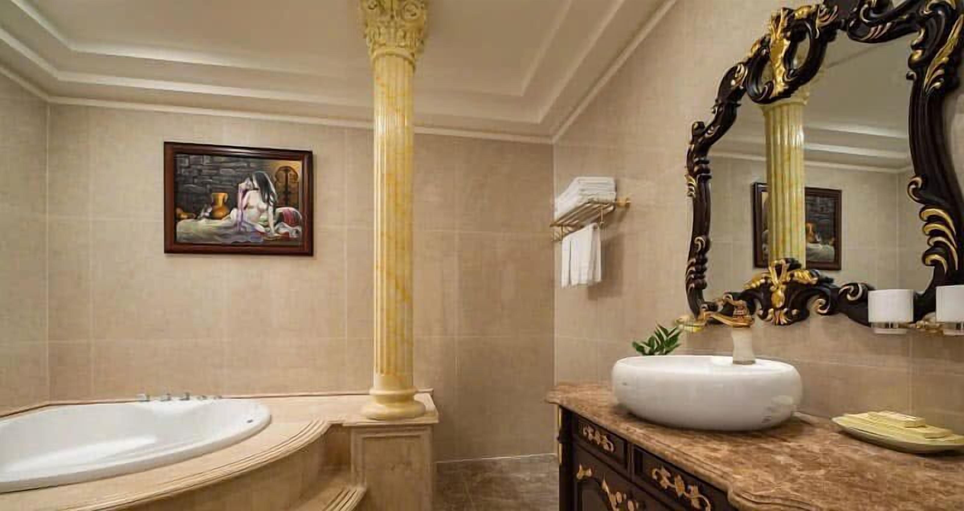 Casa de banho com banheira, um espelho grande e toucador de mármore.