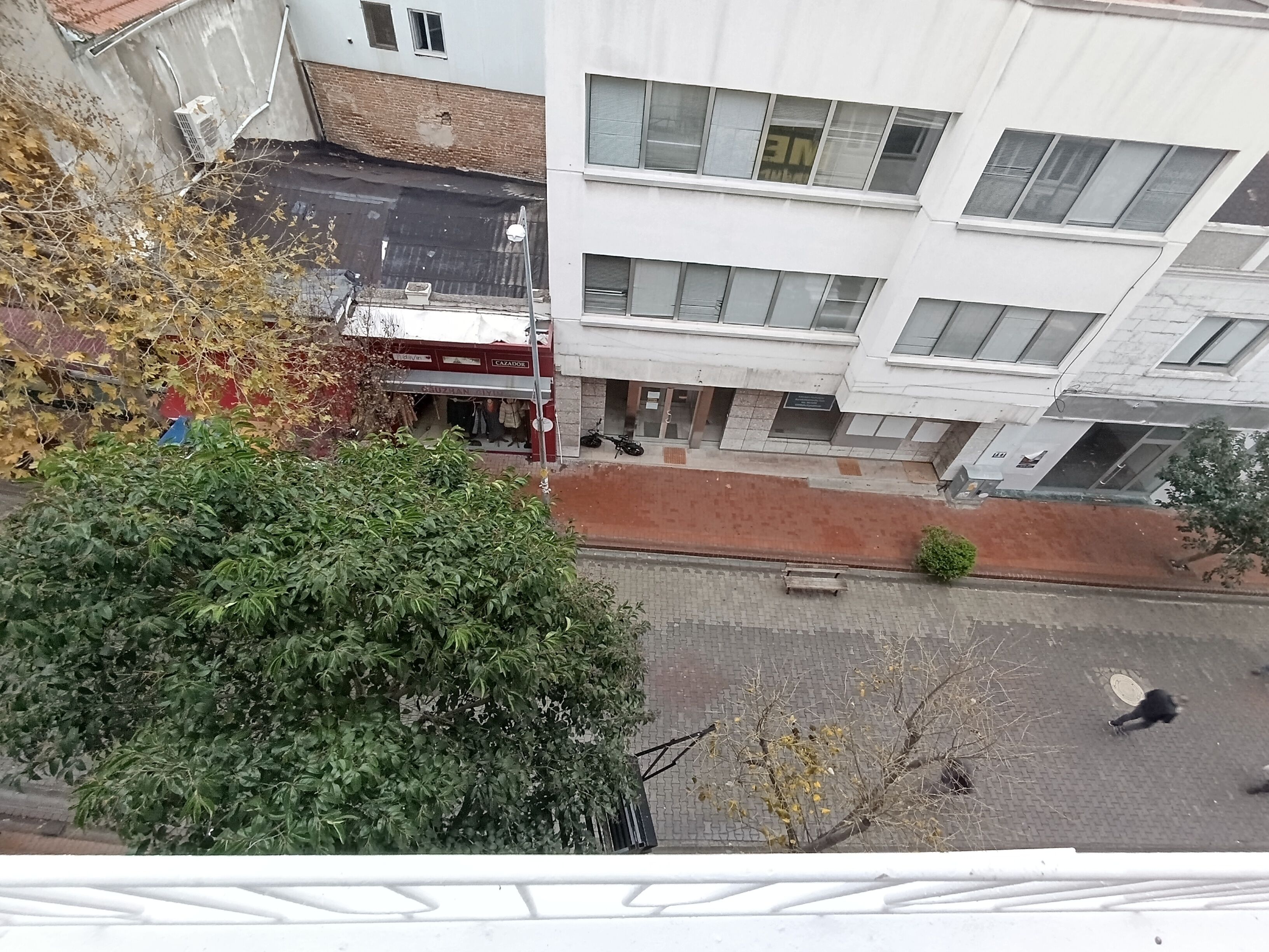 Um edifício de vários andares com entrada no nível da rua, fachada visível e caminho para pedestres.
