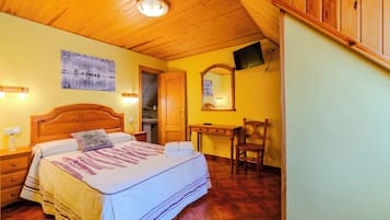 Quarto com teto de madeira, cama com colcha listrada, escrivaninha com cadeira, espelho e televisão na parede.