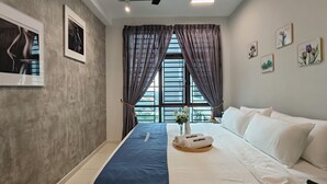 Quarto de hotel com uma cama grande, um ventilador de teto, uma janela com cortinas e quadros nas paredes.