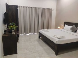 Quarto de hotel com uma cama, uma mesa de cabeceira e uma luminária, e uma cortina.