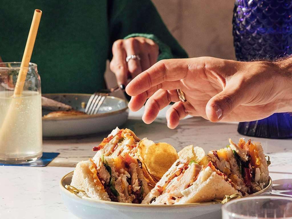Um prato de sanduíches e um copo de bebida sobre uma mesa.