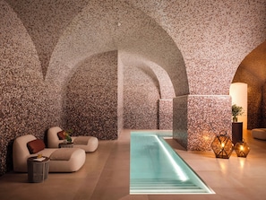 Uma área de spa moderna com piscina, assentos e iluminação decorativa.
