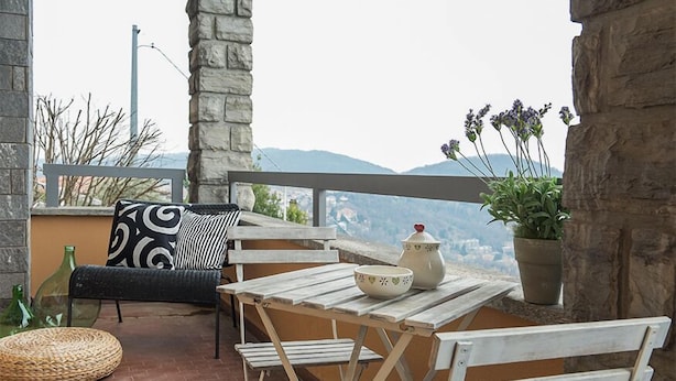 Um terraço com uma mesa de madeira, um banco e um vaso de planta.
