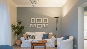 Uma sala de estar moderna com parede cinza, sofá branco, mesa de centro de madeira e luminária de chão.