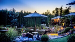 Um jardim tranquilo com lago, mobiliário de pátio e um gazebo.