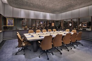 Uma sala de conferências com uma mesa comprida, várias cadeiras e diversos equipamentos de escritório.