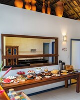Mesa de buffet com diversos alimentos e um espelho grande acima.