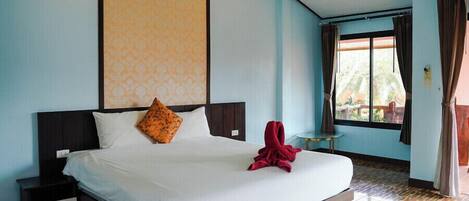 Quarto de hotel com uma cama grande, mesa de cabeceira pequena, janela com cortinas e vista para o exterior.