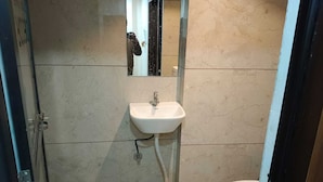Um banheiro pequeno com pia branca, espelho e vaso sanitário.