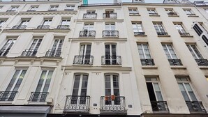 Fileira de edifícios brancos com varandas e janelas numeradas.