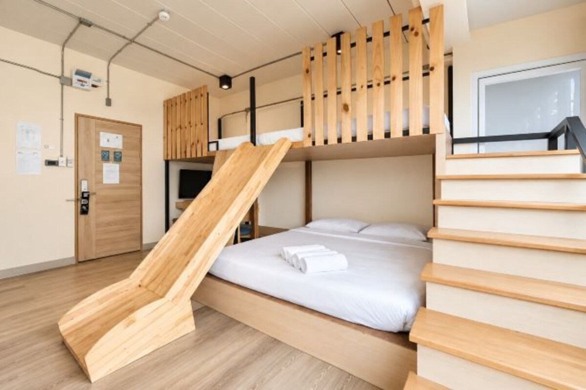 Uma cama beliche com escada de madeira e um pequeno escorregador de madeira.