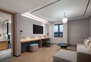 Quarto de hotel moderno com cozinha compacta, uma janela grande e um espaço para sentar.