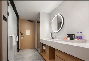 Uma casa de banho moderna com um espelho grande, uma pia e uma máquina de café.